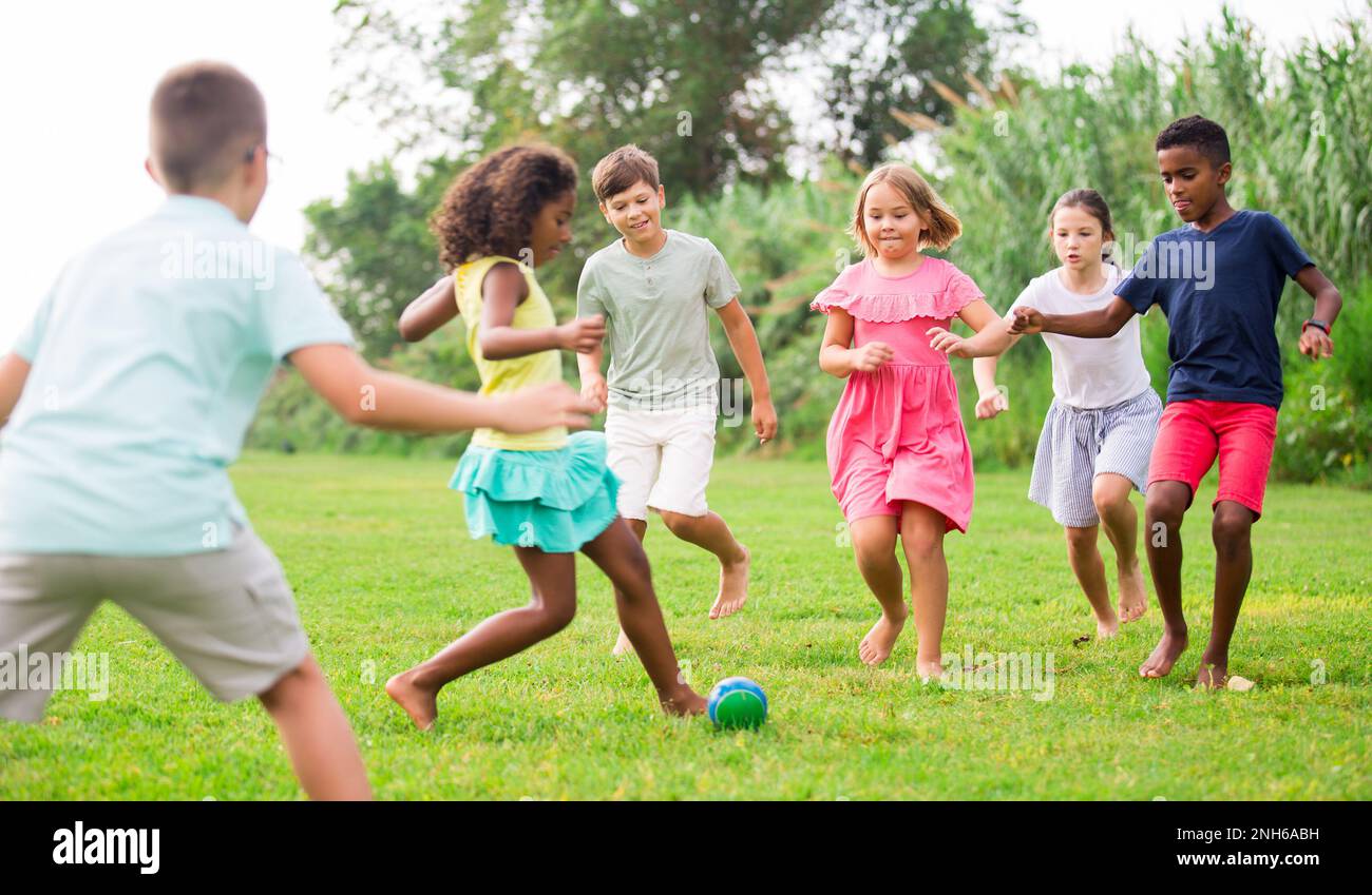 Kids running through grass and playing football Stock Photo - Alamy
