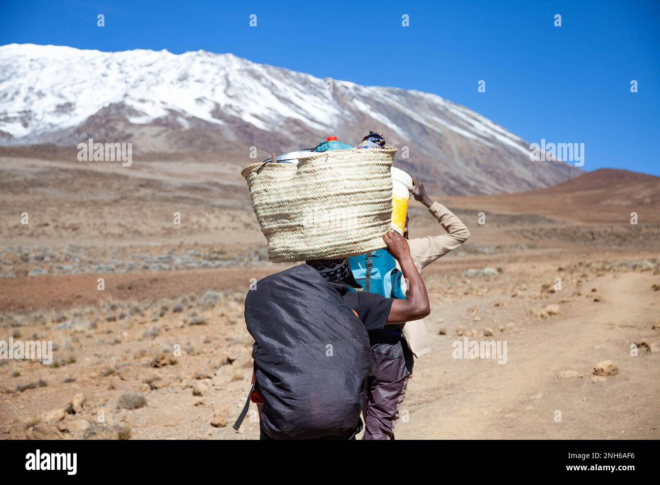 Porters carrying heavy load on his back walks along the road Stock ...