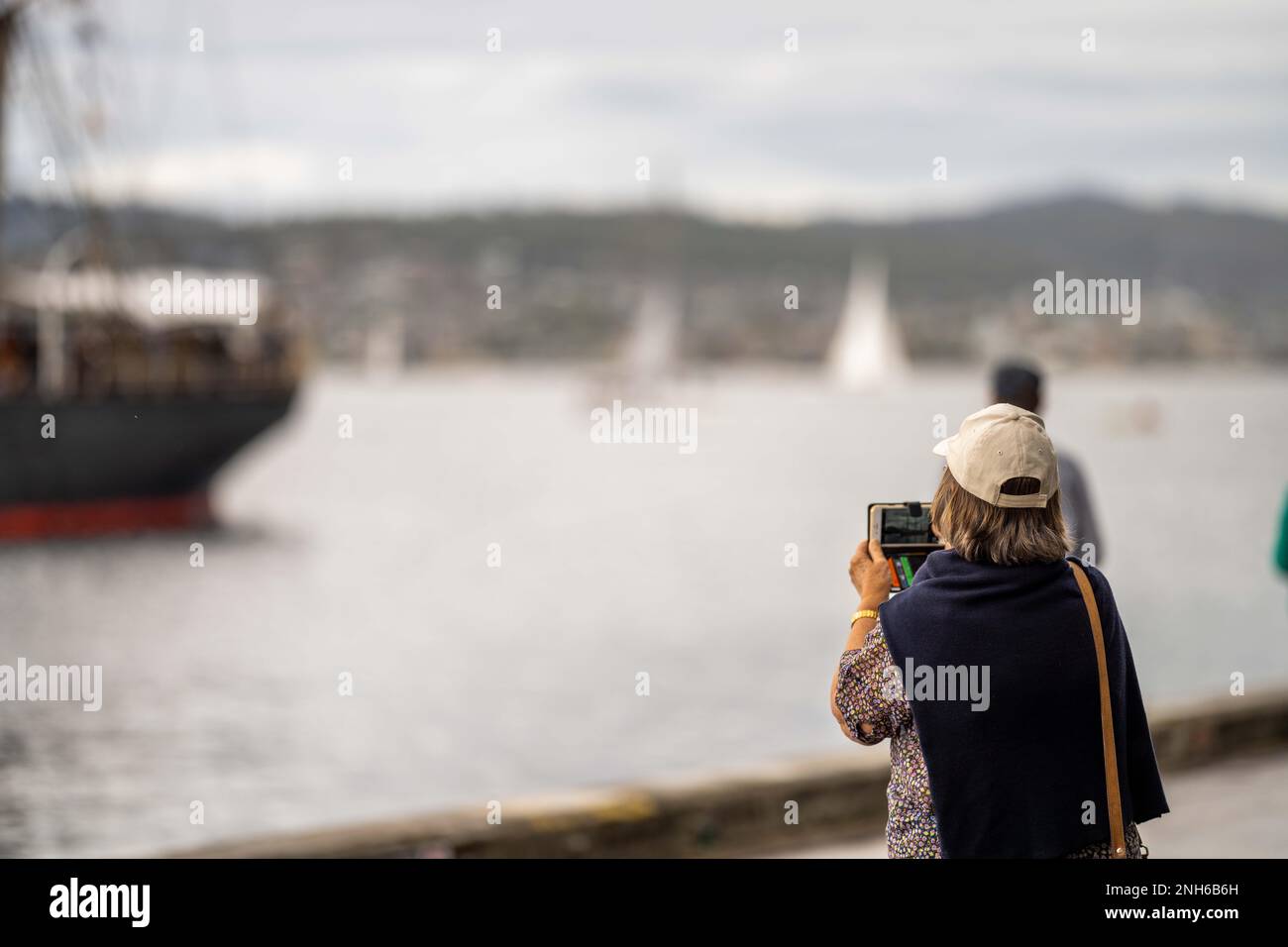 people taking photos with their phone of tall ships at a festival in ...