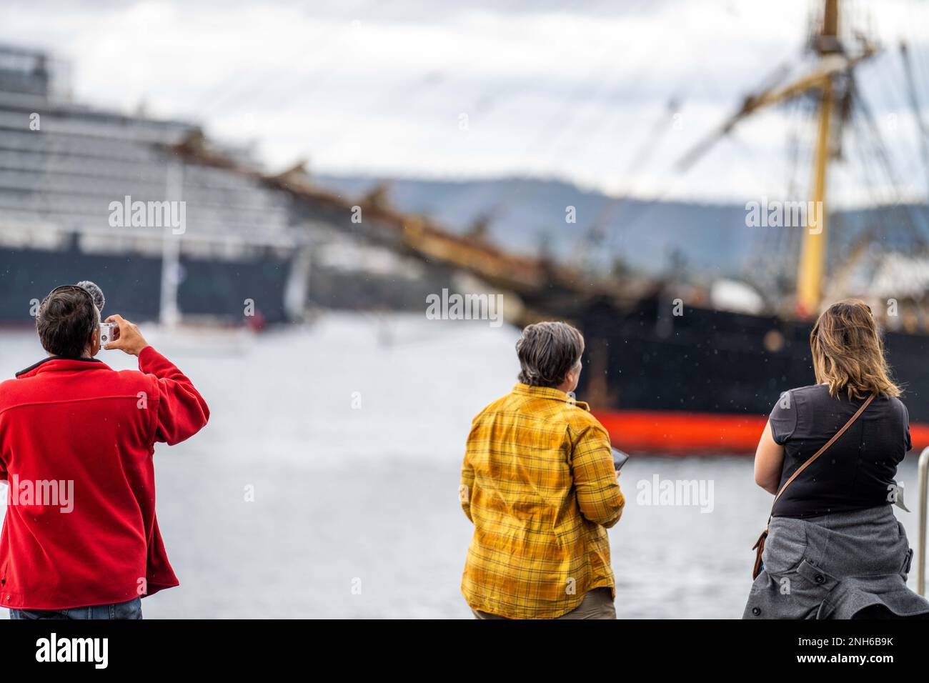 people taking photos with their phone of tall ships at a festival in ...