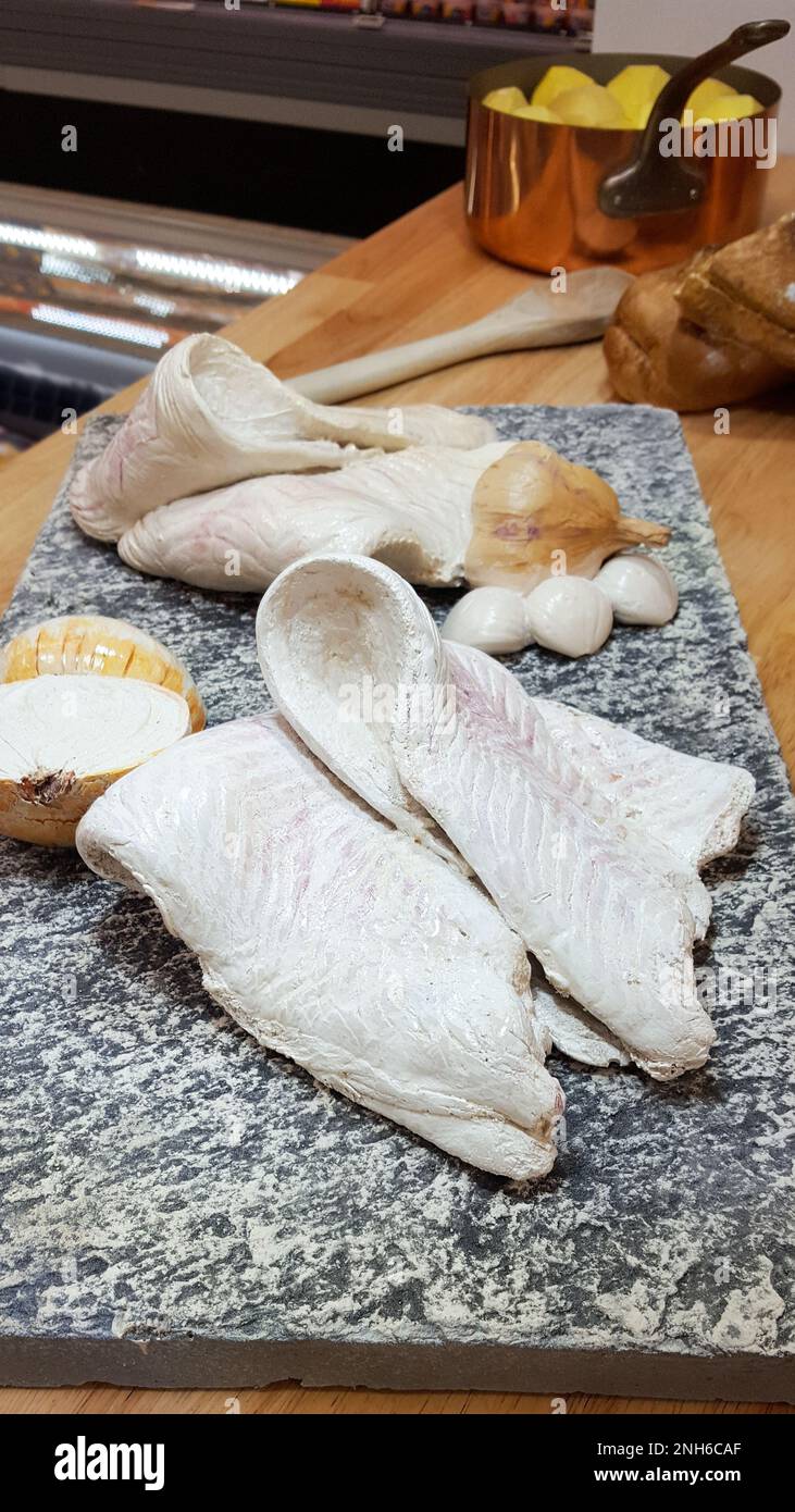 white fish fillet on marble tray with pot of potatoes and onion in the ...