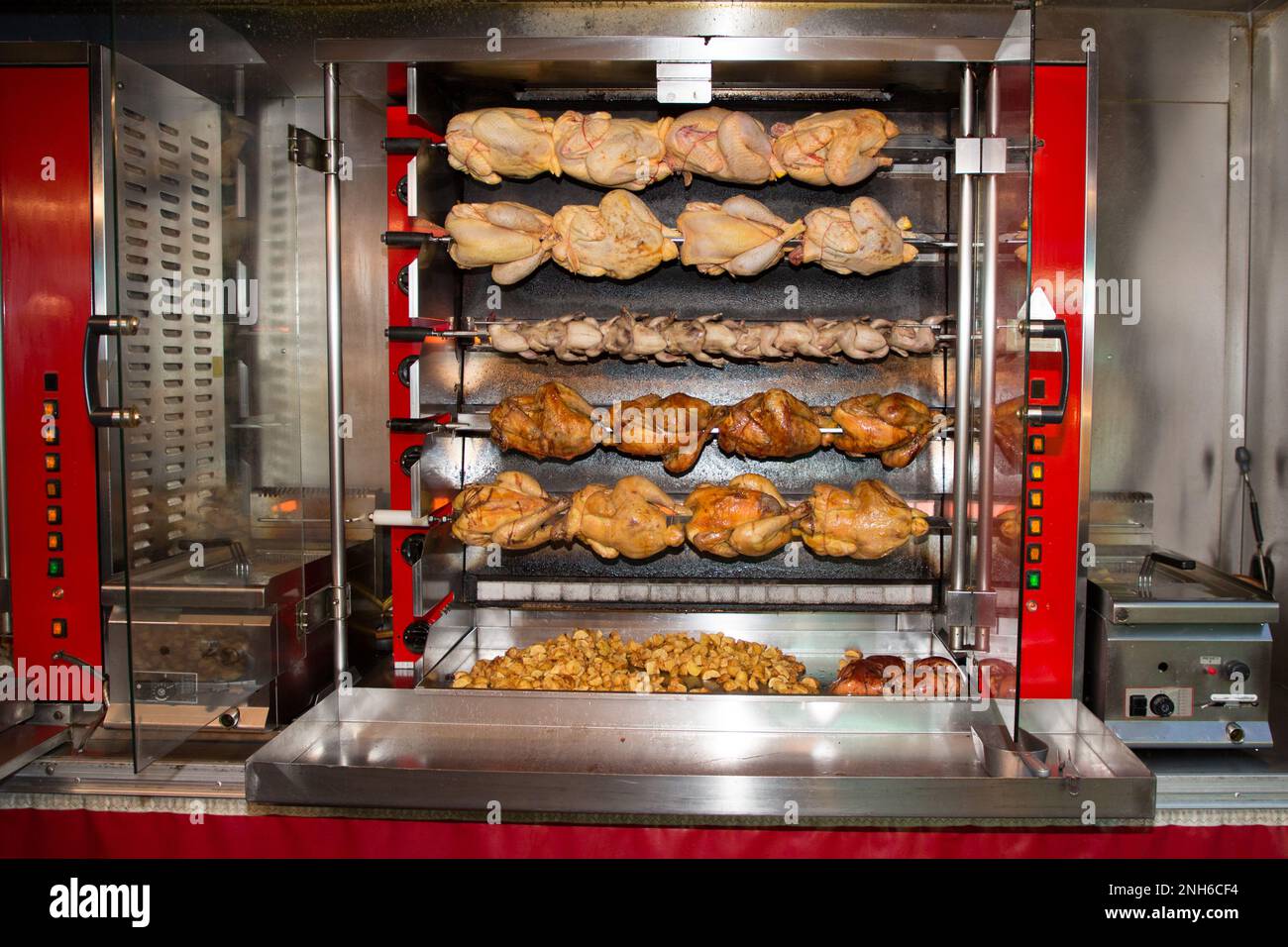 Red roasted chicken in row turning at industrial roaster at food truck ...