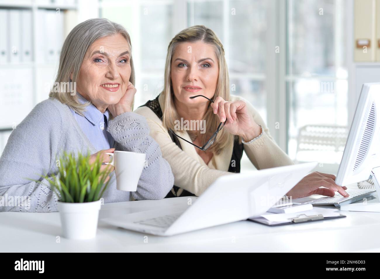 two excited mature women working in office Stock Photo - Alamy