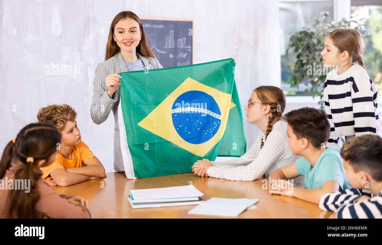 Teacher holds the flag of Brazil in her hands and tells the students ...
