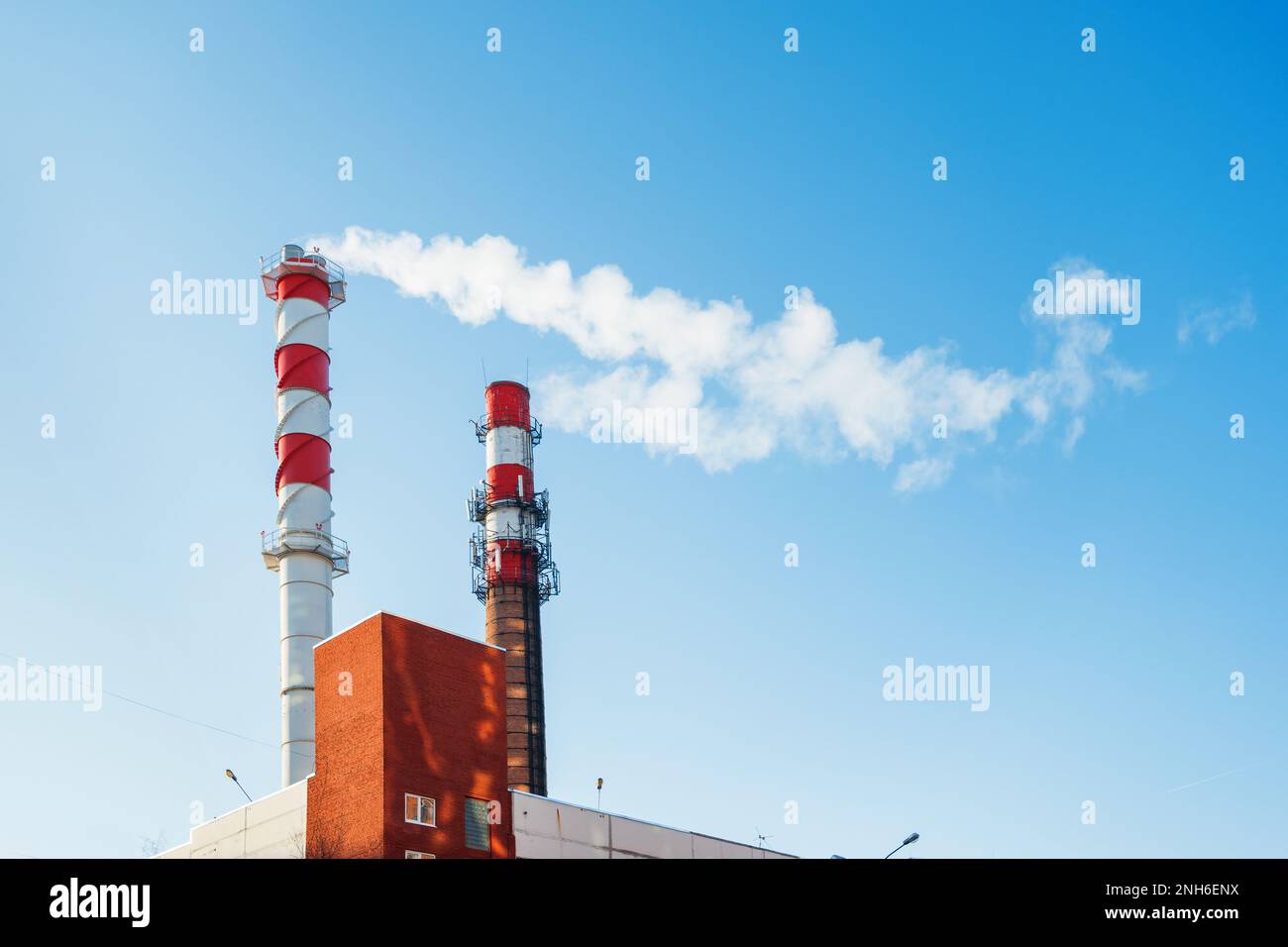 Boiler house chimney. Steam against the clear blue sky. Industrial zone ...