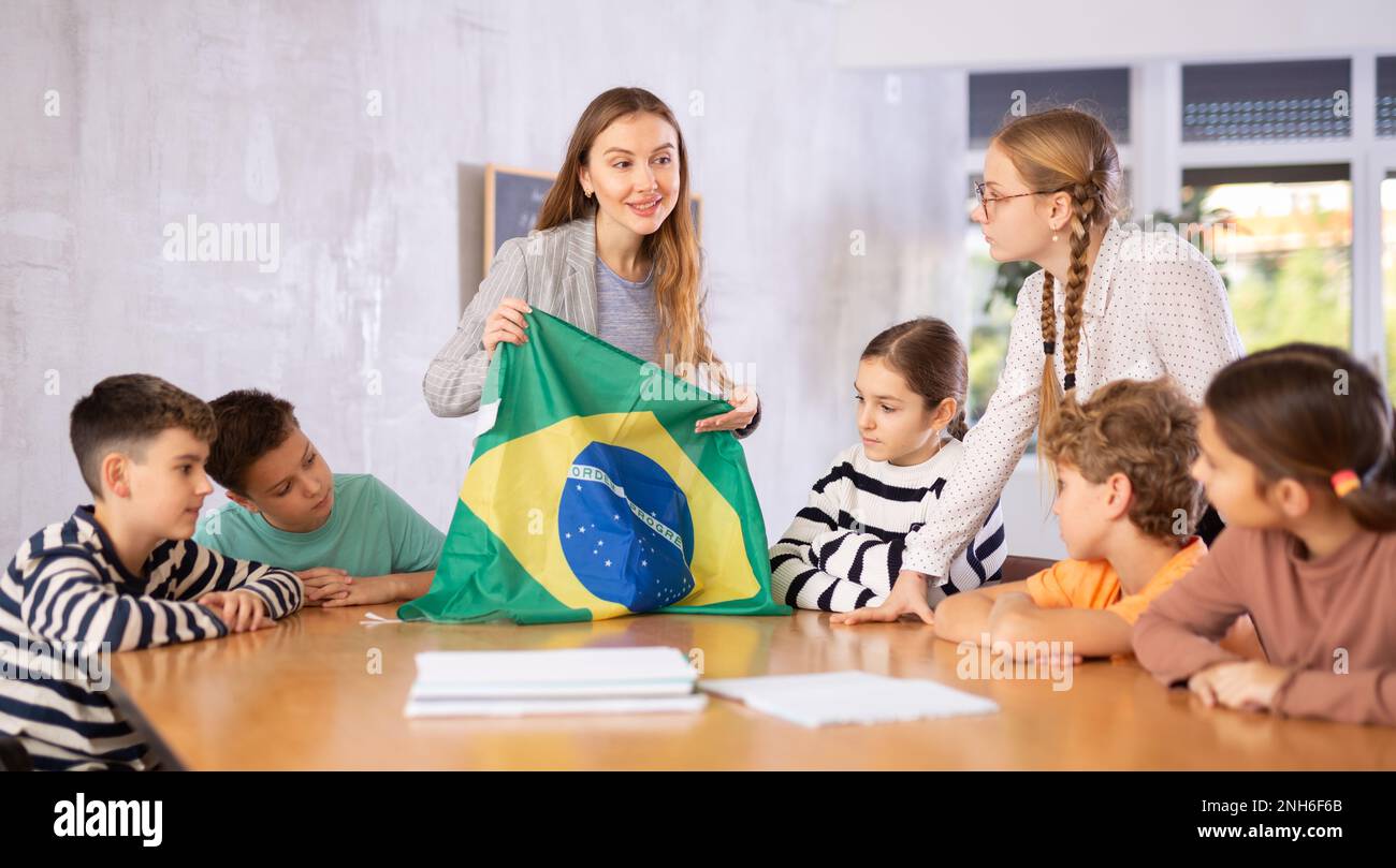 Teacher holds the flag of Brazil in her hands and tells the students ...