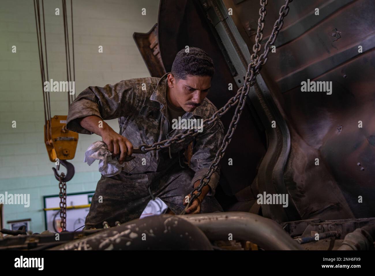 U.S. Army Mechanic places chains in preparation to lift an engine on ...