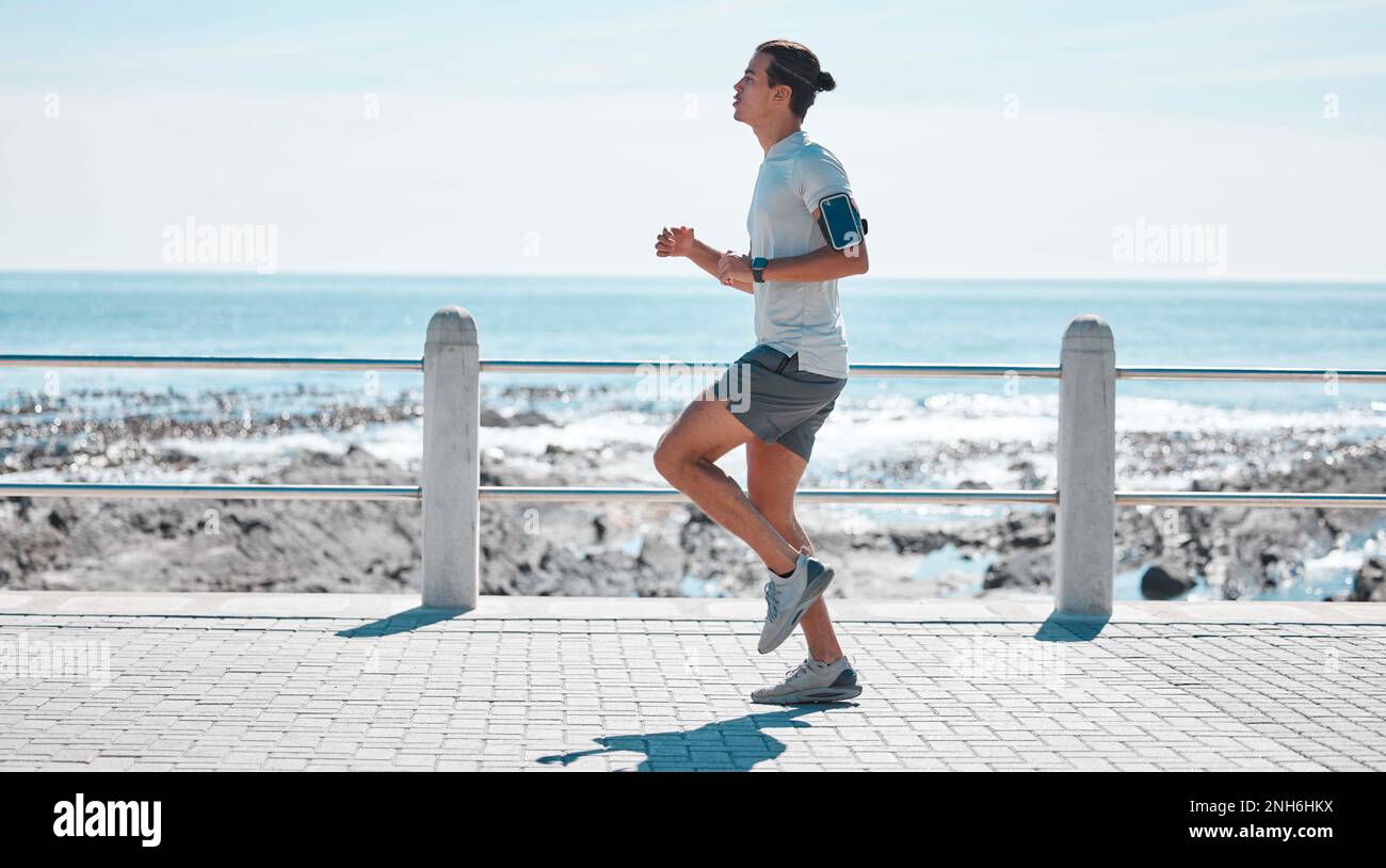 Fitness, sports and man running by ocean in action for wellness ...