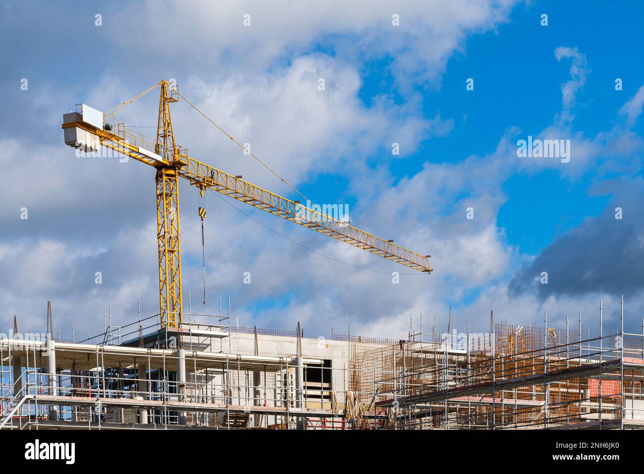 Tower crane over building under construction in scaffolding. Blue sky ...