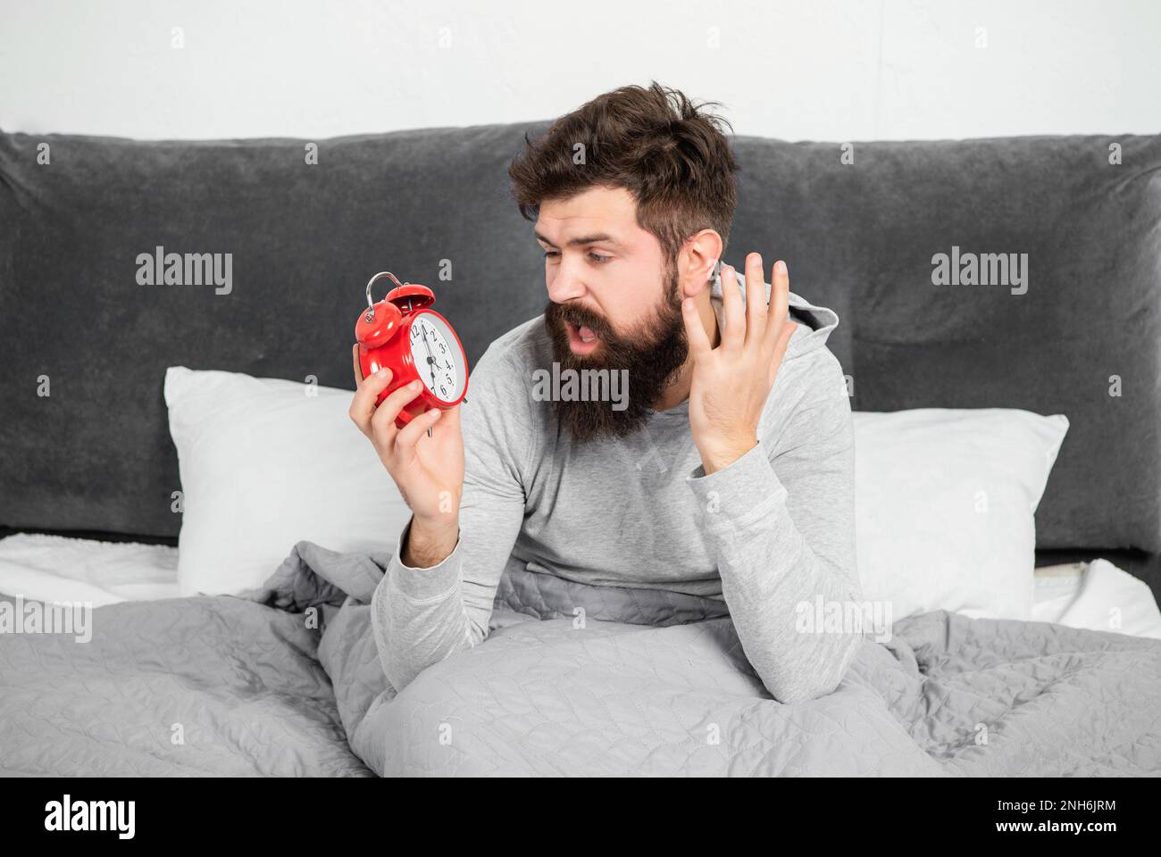 Angry man shouting at alarm clock being in bed awake in morning ...