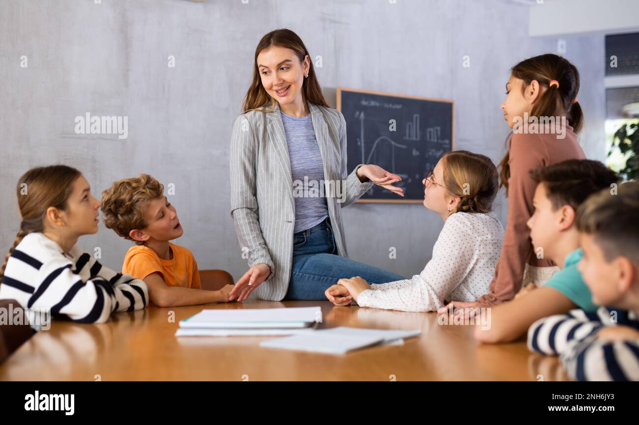Focused preteens school children listening to young woman teacher ...