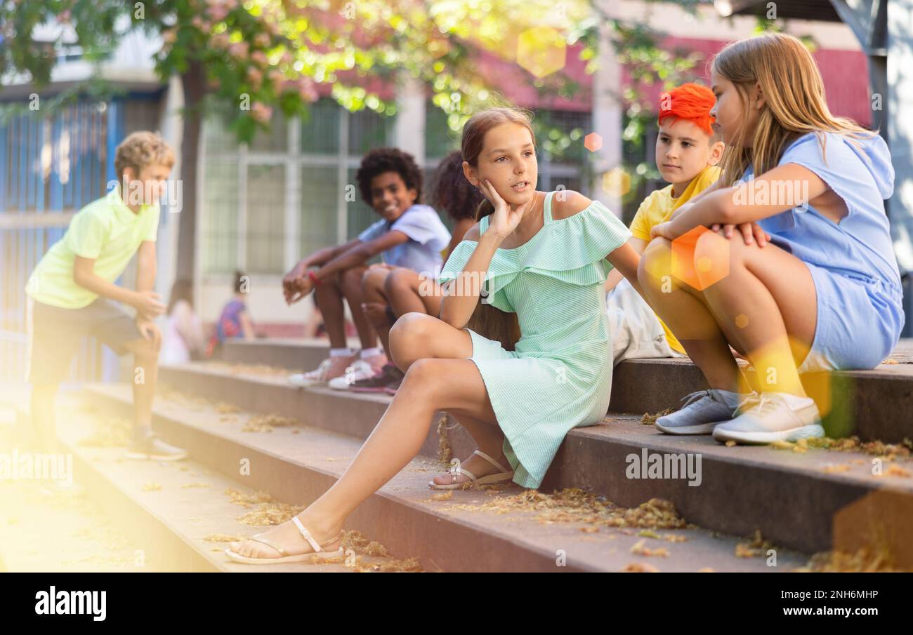 Children talking together while sitting on stairs outdoors Stock Photo ...
