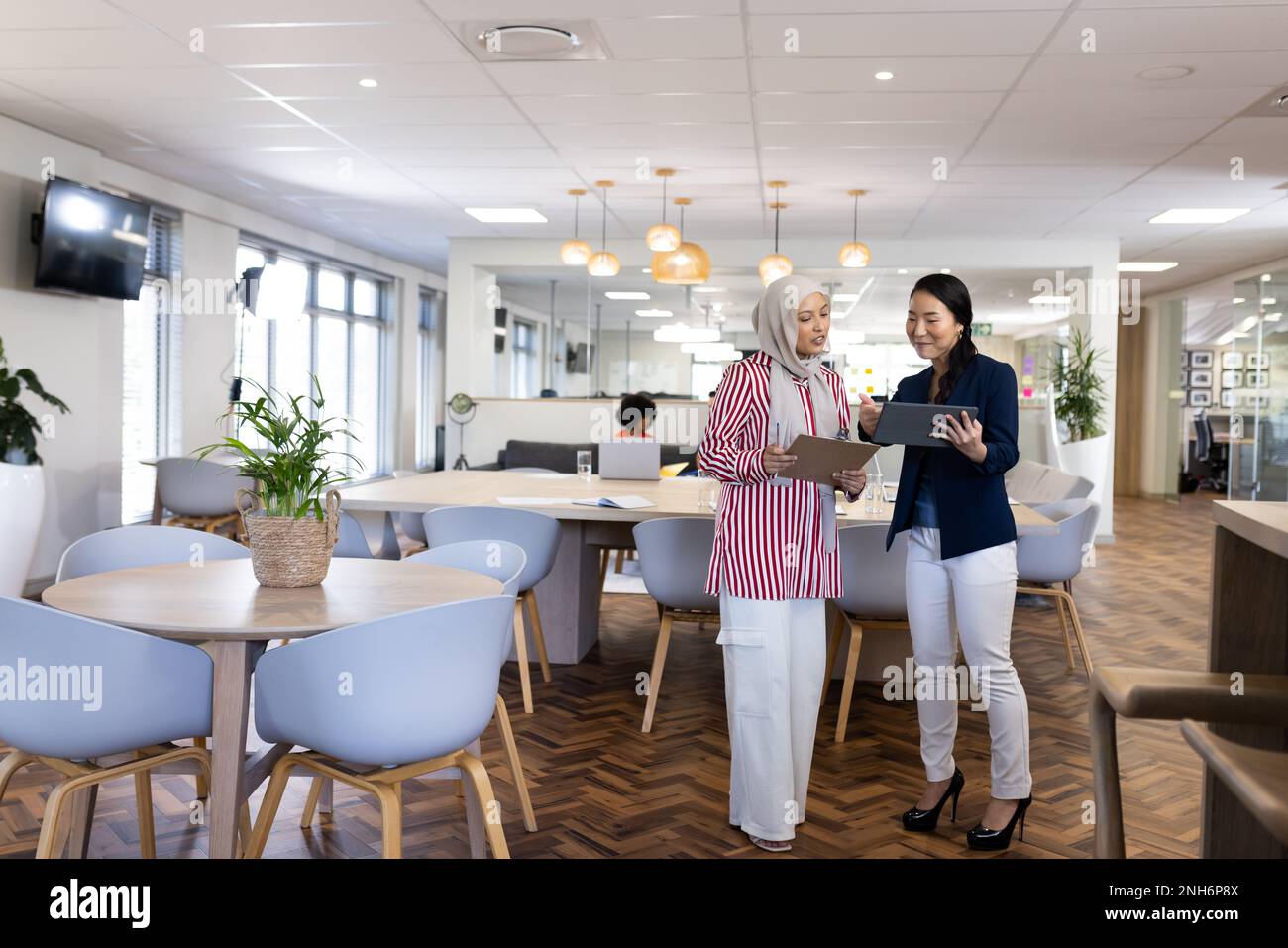 Happy diverse businesswomen with tablets talking in office lounge Stock ...