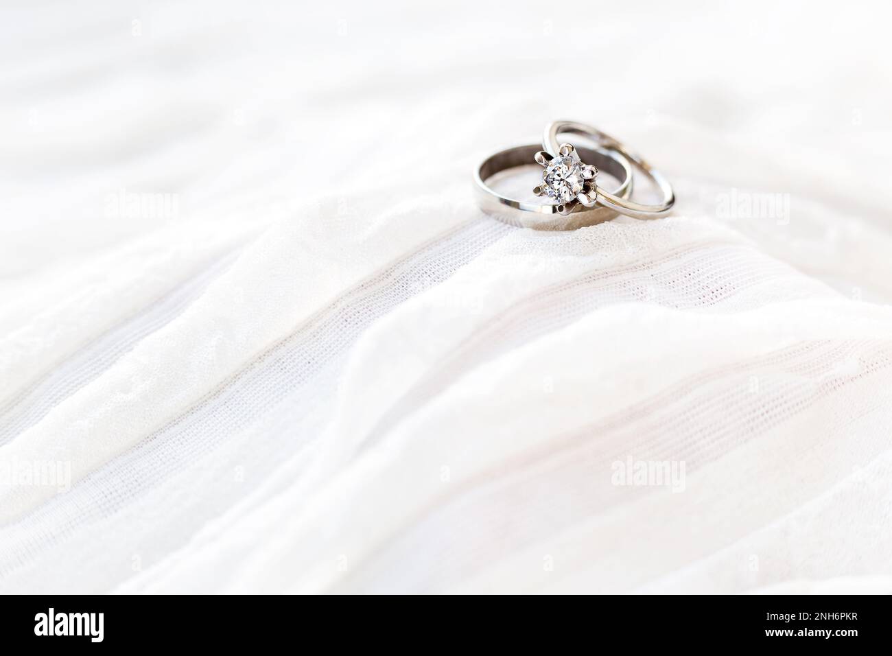 Golden wedding rings with diamond lie onwhite fabric. Symbol of love ...
