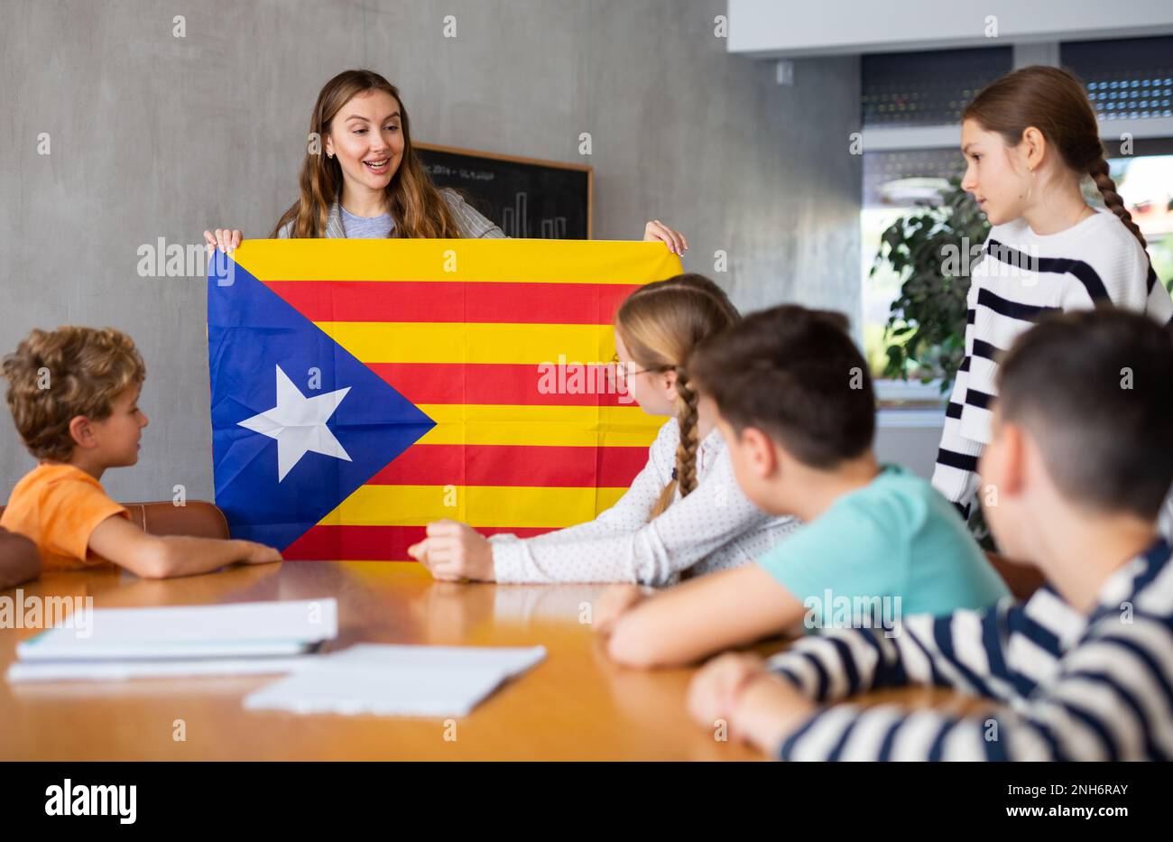 Young female teacher holding colorful flag of Estelada while working ...