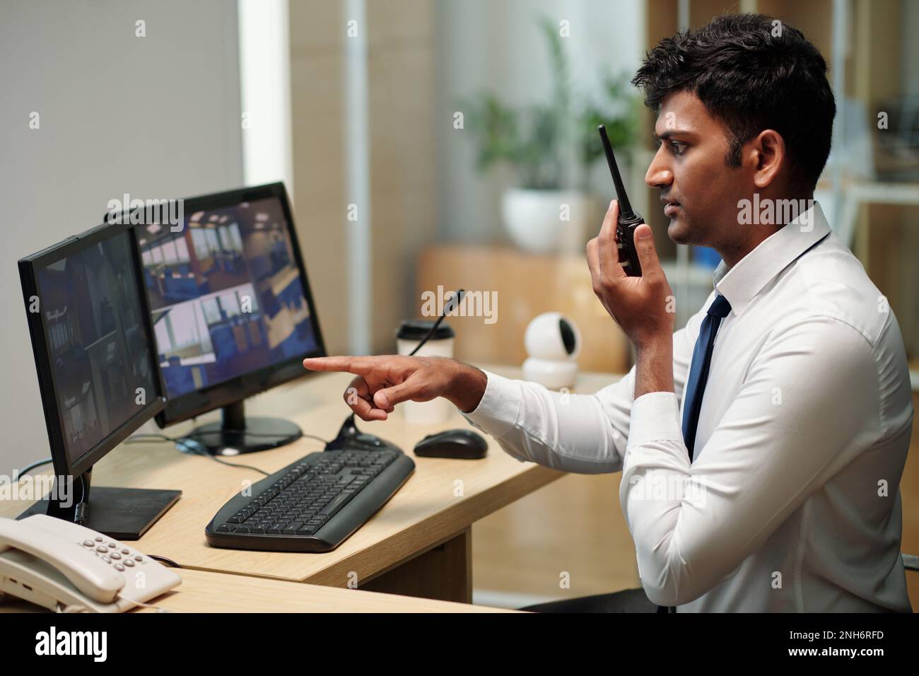 Security guard communicating to coworkers via walkie-talkie when ...