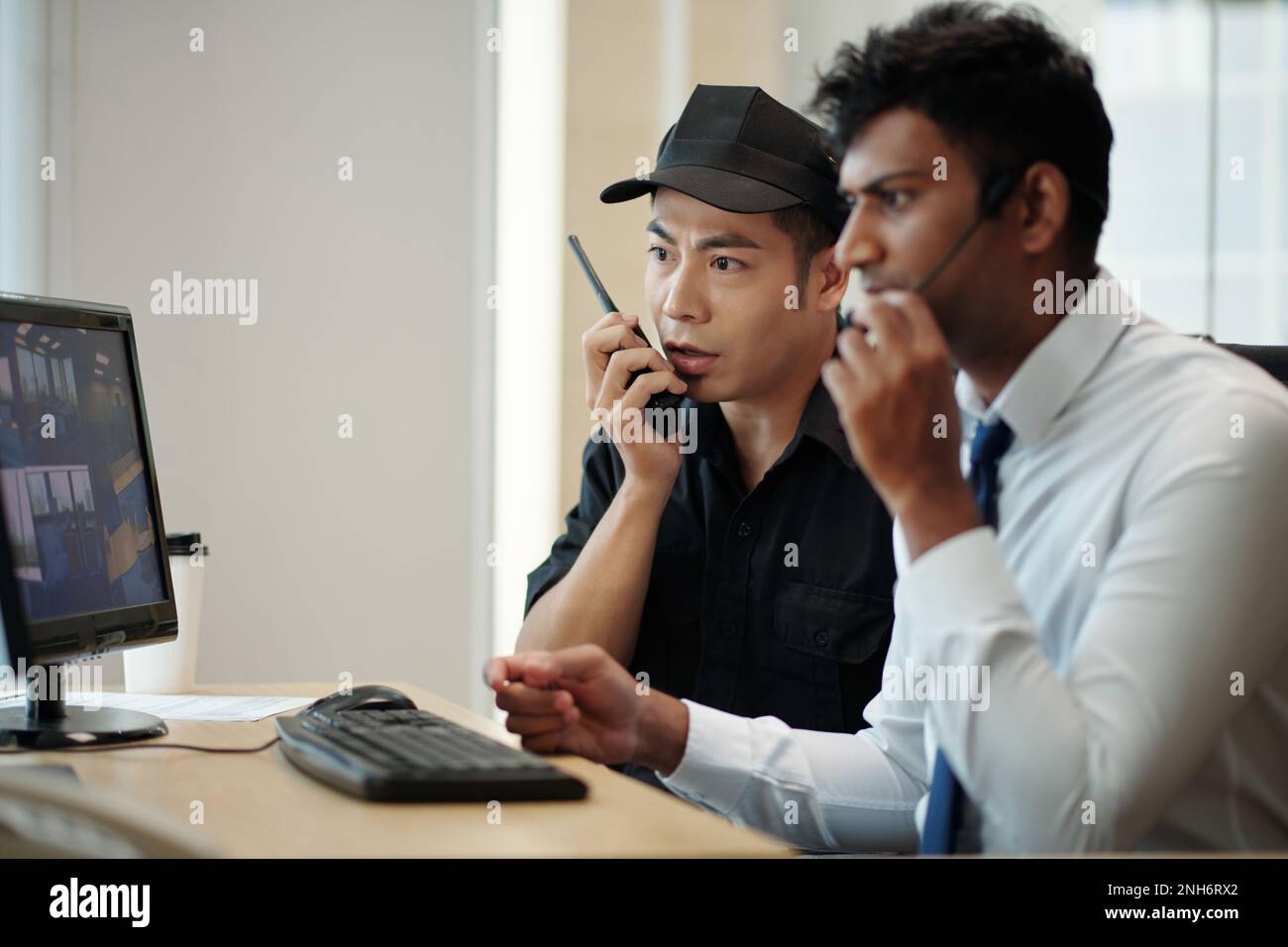 Security guards looking at monitor and speaking in walkie-talkie Stock ...
