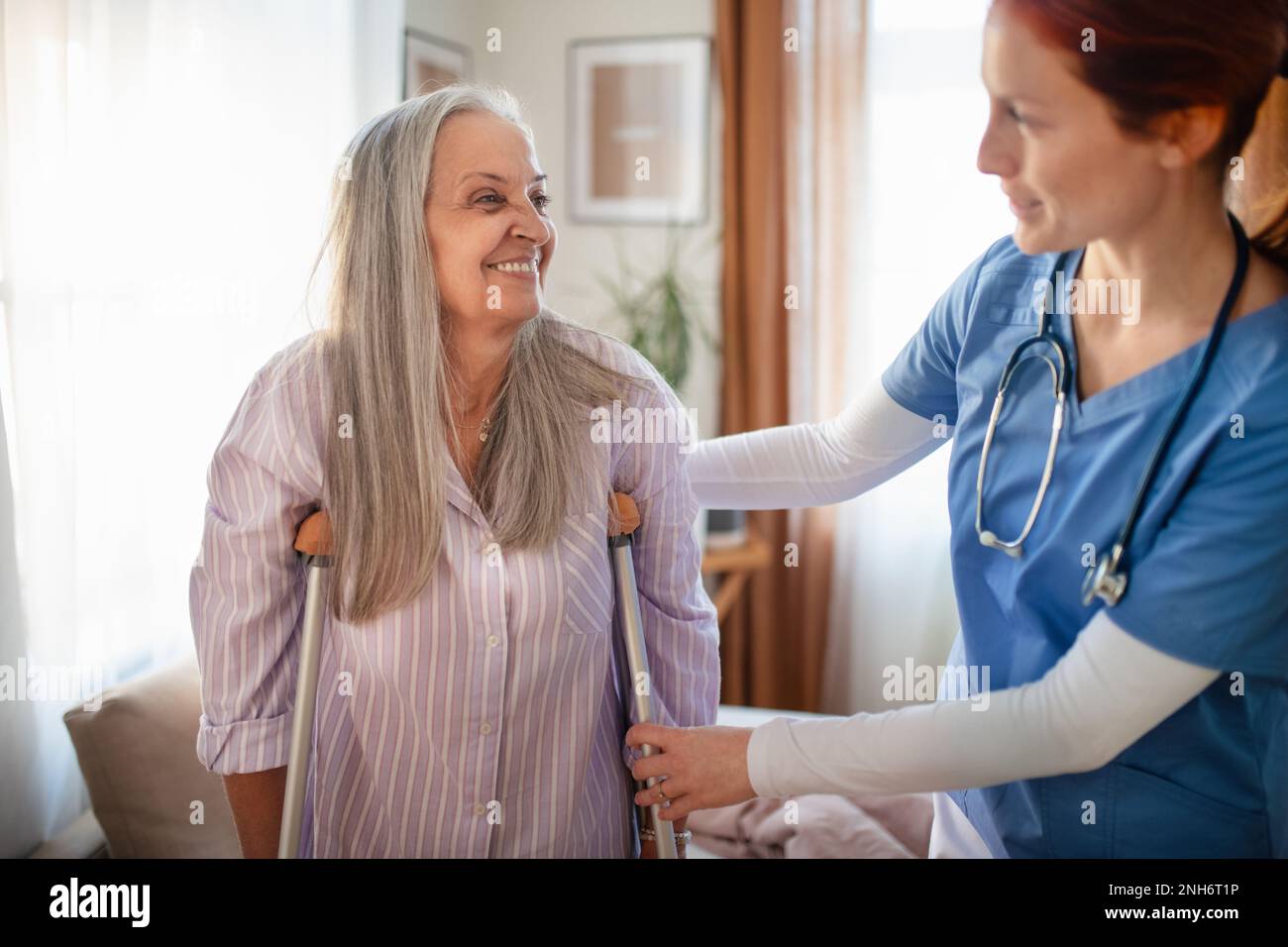 Nurse helping senior woman with walking after leg injury Stock Photo ...