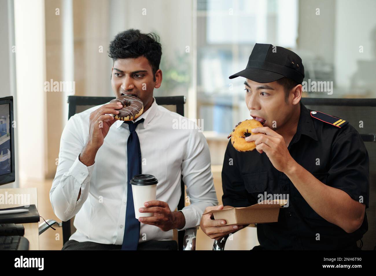 Security guards eating glazed donuts during coffee break Stock Photo ...