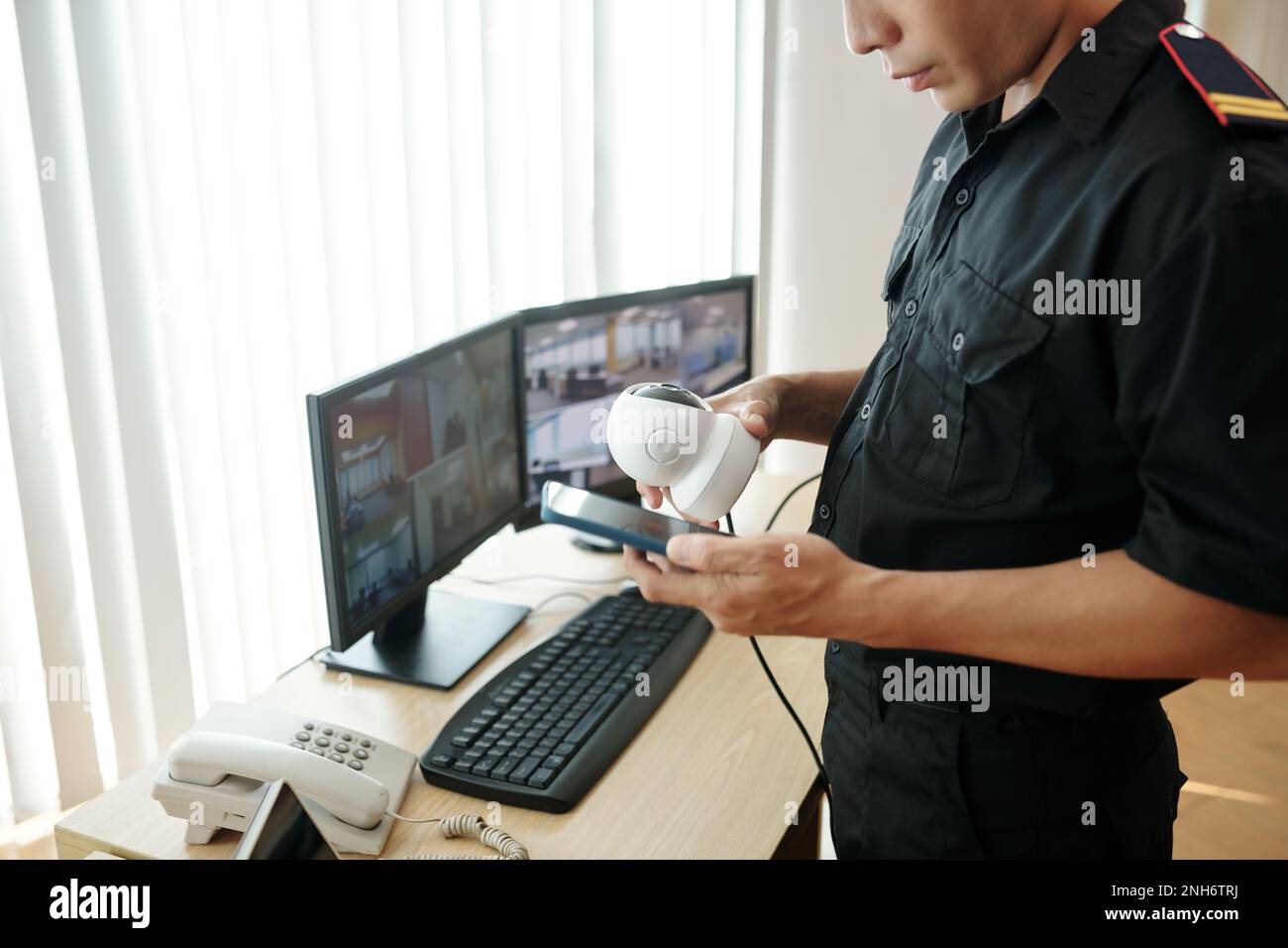 Security guard uploading footage from surveillance camera on smartphone ...
