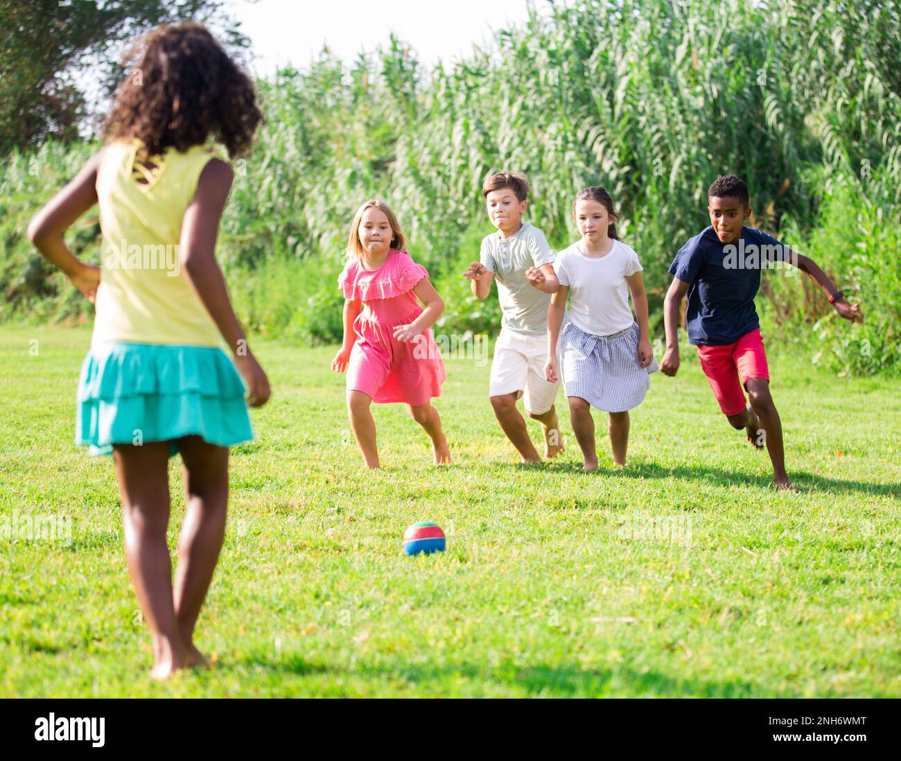 Cheerful tween friends playing with ball outdoors in summer Stock Photo ...