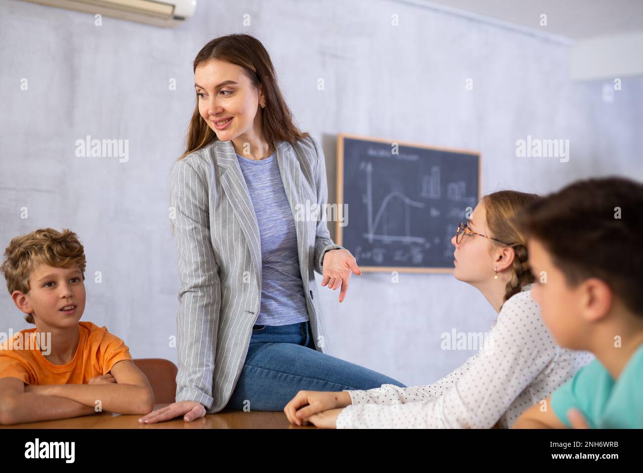 Focused preteens school children listening to young woman teacher ...