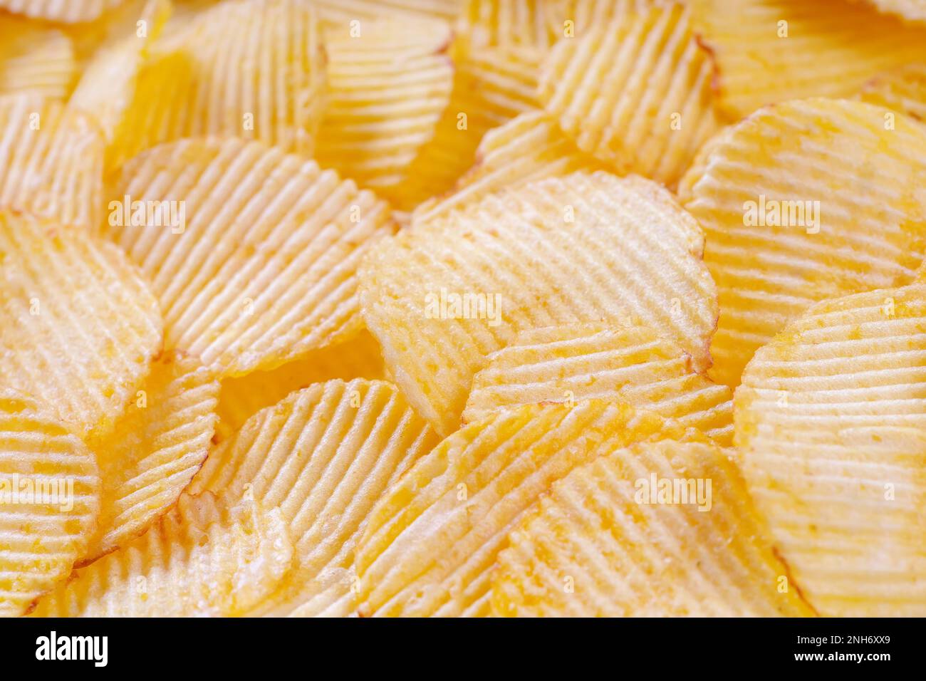 Yellow crispy ridged potato chips close up. Food background, banner ...