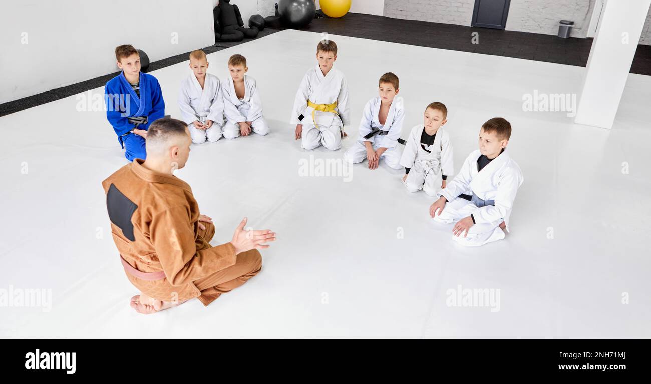 Group of little boys, children in kimono sitting on floor around coach ...