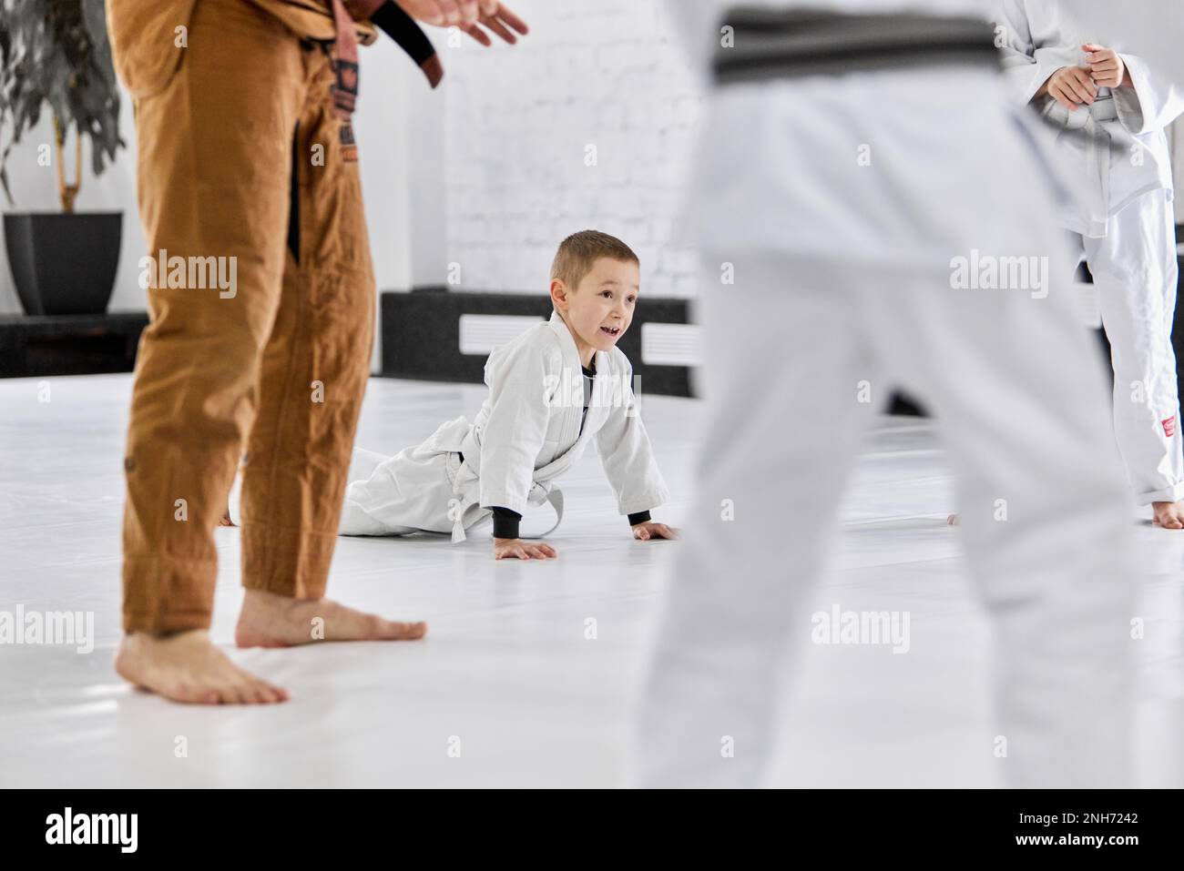 Little active boy, child in white kimono attending martial arts school, learning judo, jiu-jitsu ...