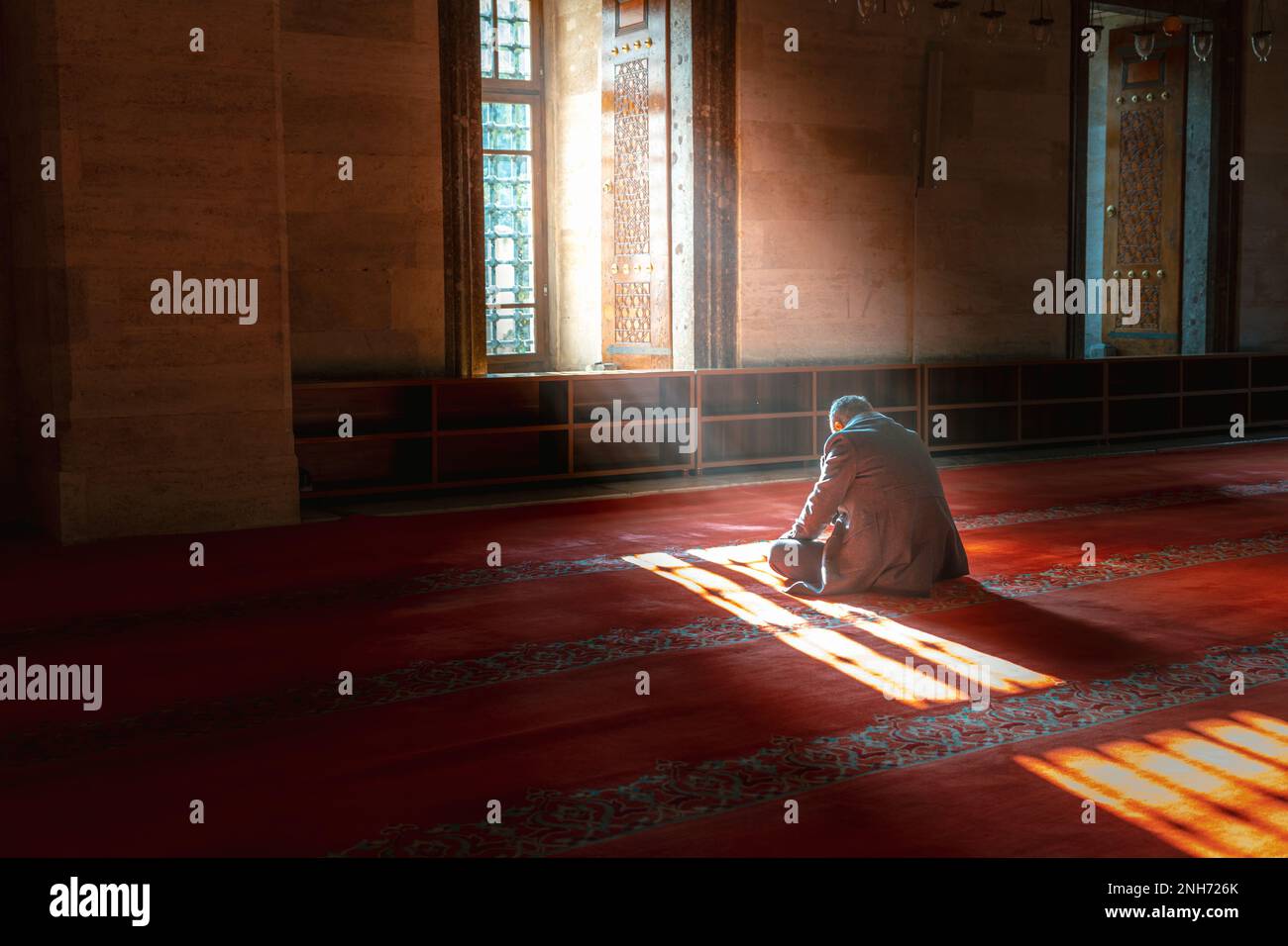 Islamic photo. Muslim man praying in the mosque. Sunlight rays and haze ...