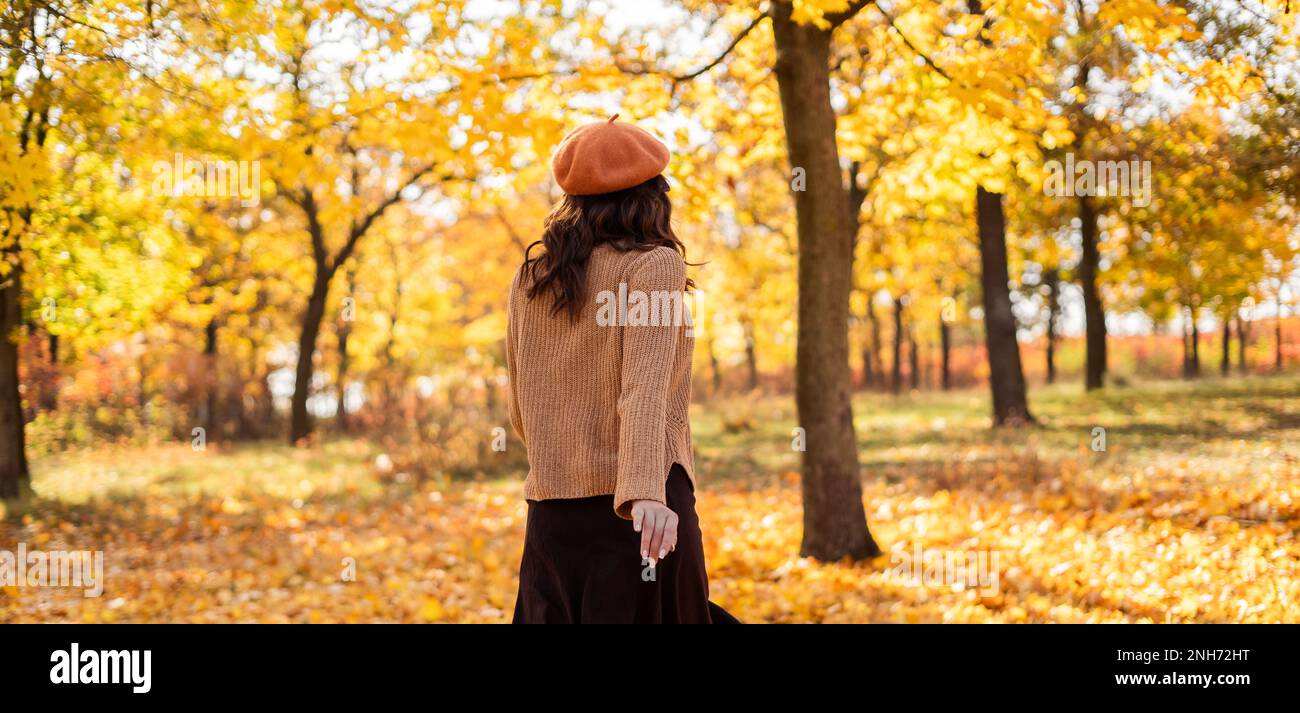Rear view of brunette girl in autumn park in sweater. Back view of ...