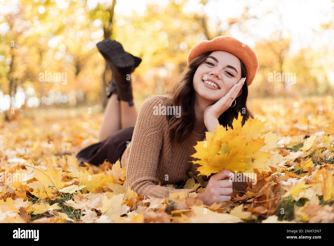 Beautiful young woman in park in fall holding leaves. Brunette teenage ...