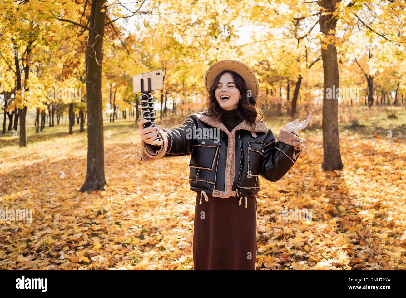 Happy young woman vlogging with an phone mounted on a flexible tripod ...