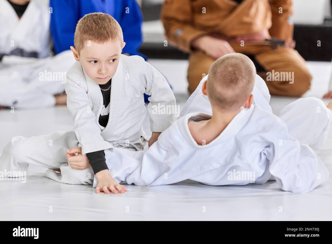 Boys, children in white kimono training judo, jiu-jitsu fight style indoors. Developing strength ...