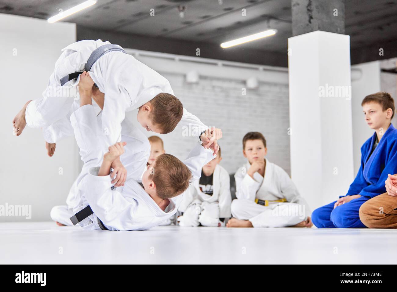 Dynamic portrait. Boys, children in white kimono training, practising judo, jiu-jitsu exercises ...