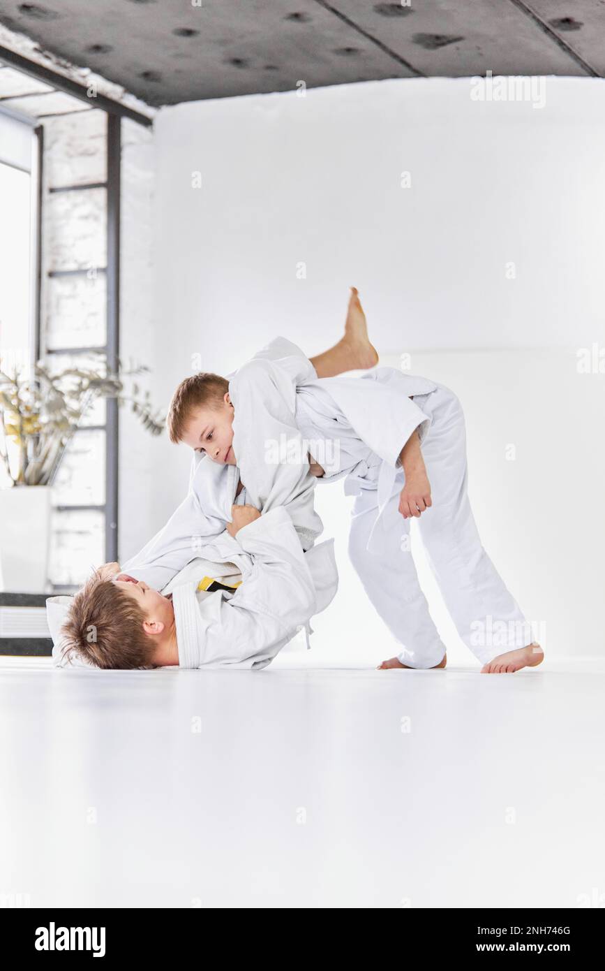 Professional exercises. Boys, children in white kimono training, practising judo, jiu-jitsu ...