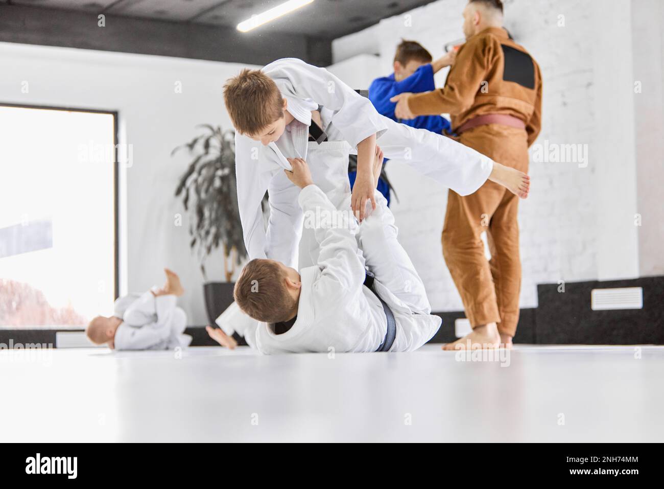 Professional sport exercises. Boys, children in white kimono training, practising judo, jiu ...