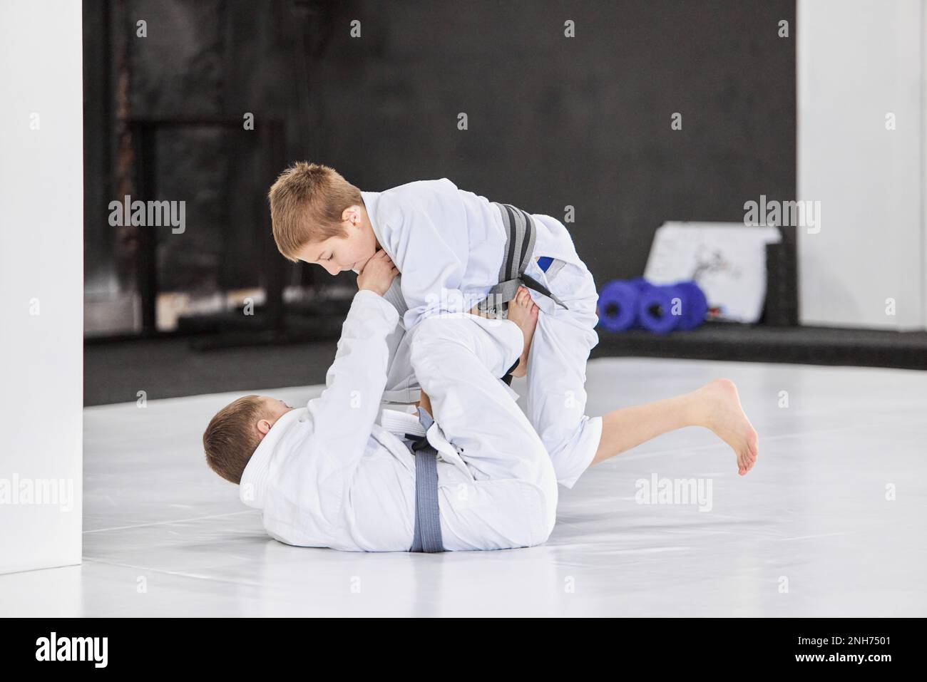 Boys, children in white kimono training, practising judo, jiu-jitsu exercises indoors. Growing ...