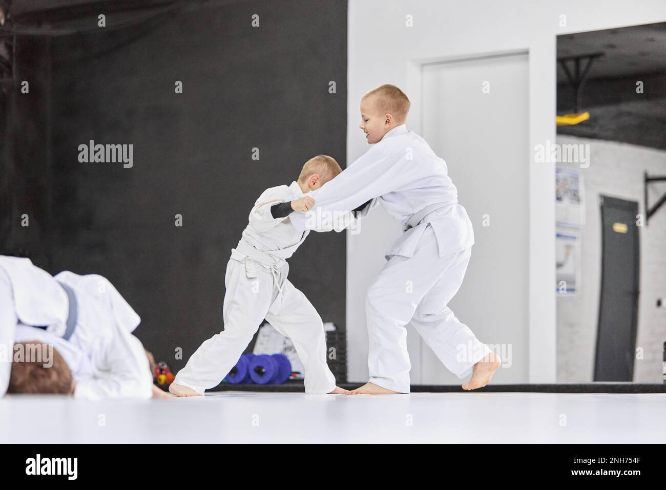 Defense. Boys, children in white kimono training, practising judo, jiu-jitsu exercises indoors ...