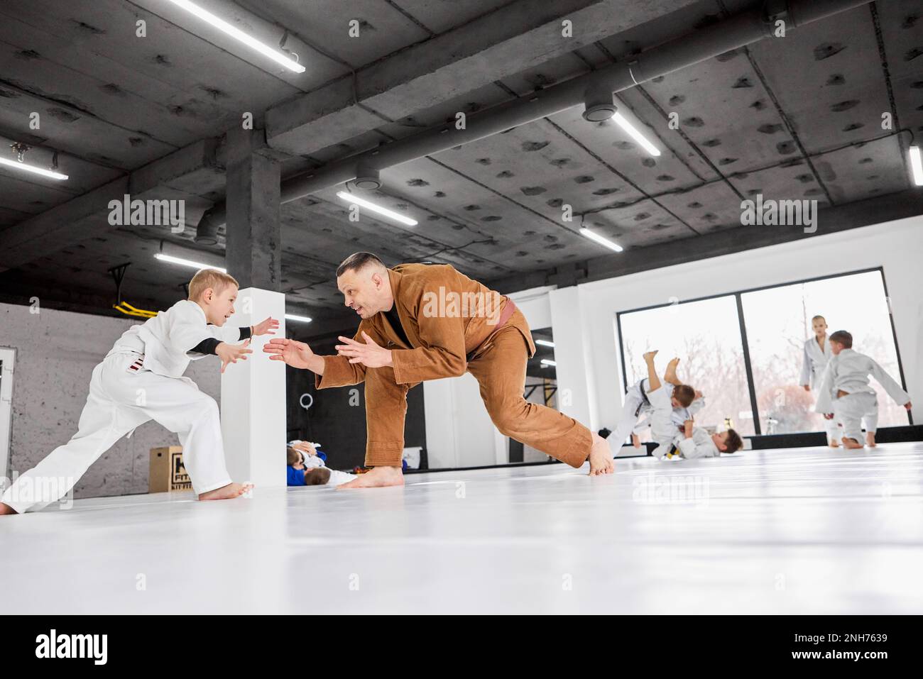 Dynamic portrait of man, professional judo, jiu-jitsu coach training with little boy, child in ...