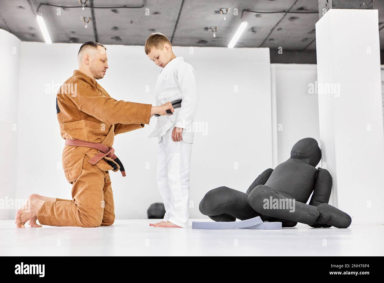 Man, judo, jiu-jitsu coach helping boy, kid to tie belt on kimono ...
