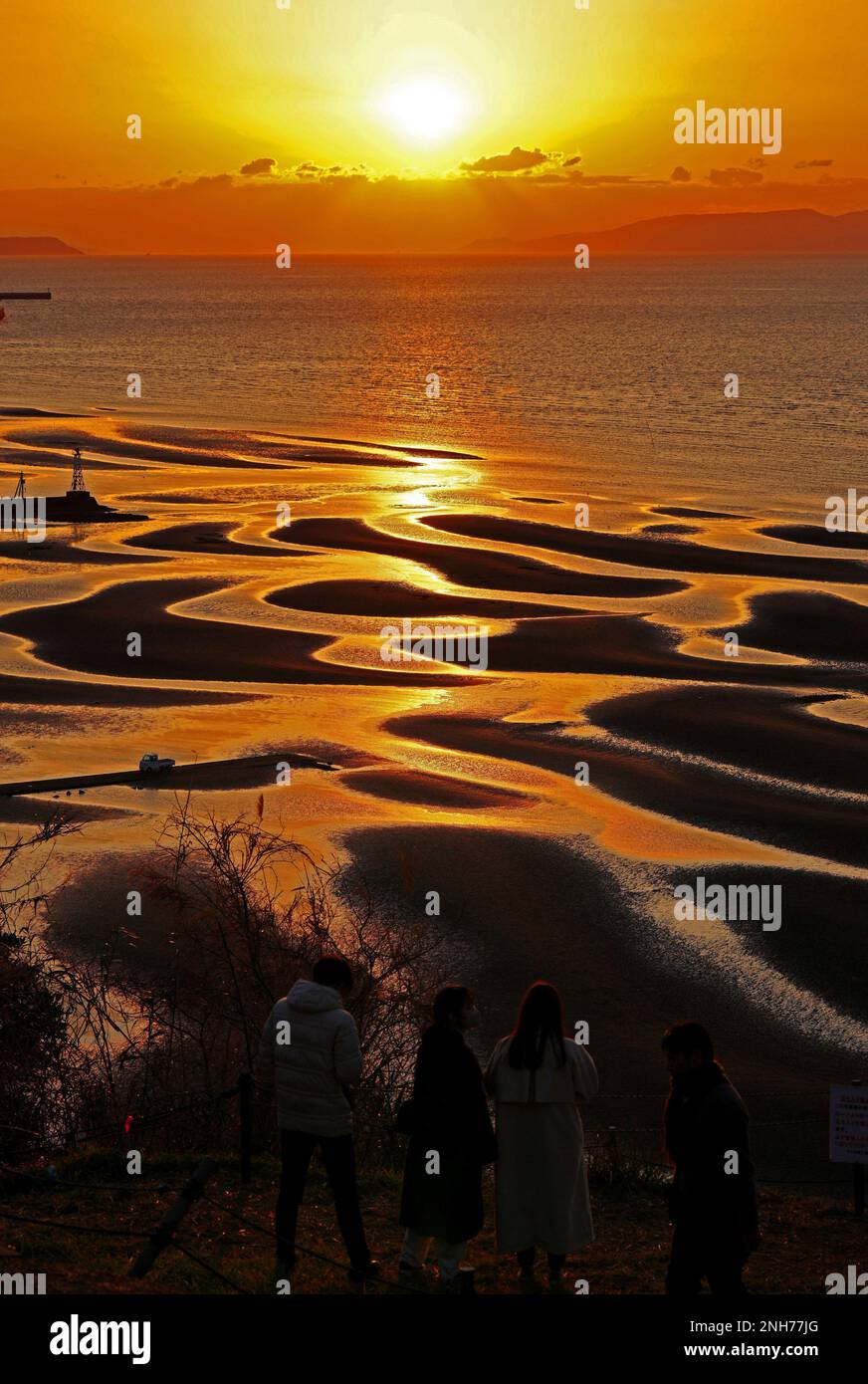 A tideland is silhouetted with the setting sun at Okoshiki Beach in Uto ...