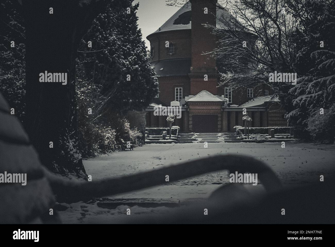 A picturesque snowy pathway lined with trees leading up to a red brick ...