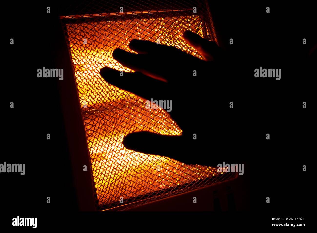 Heat from a hot home electric heater warms the hand on a black ...