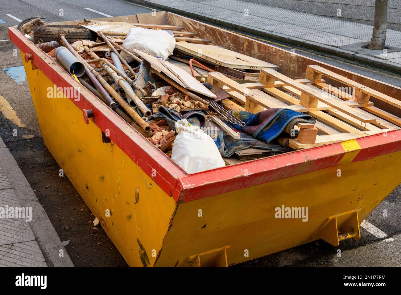 Yellow construction dumpster with a pile of debris and trash from the ...