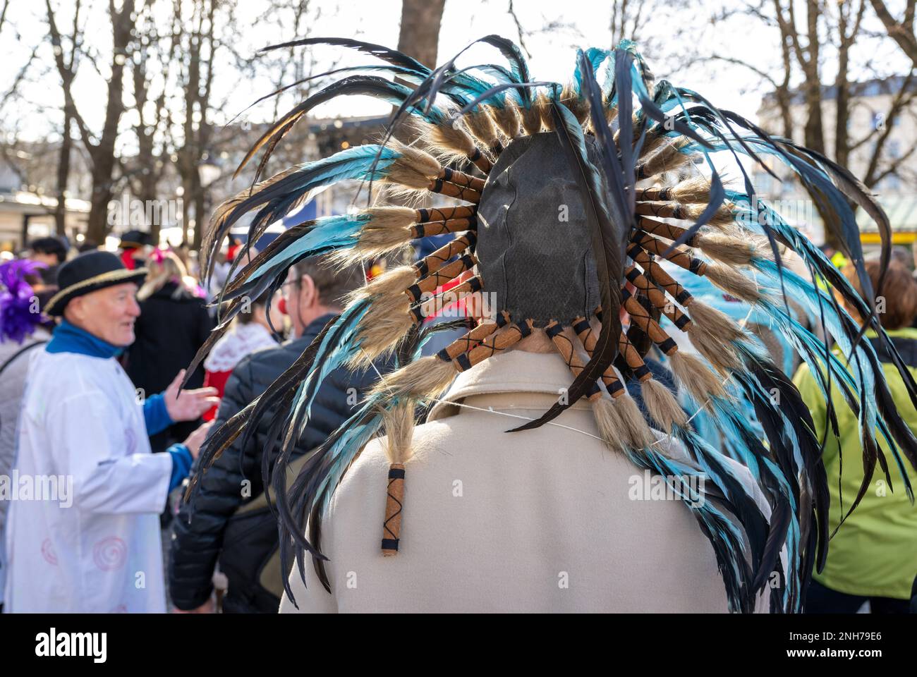 Munich, Germany. 21st Feb, 2023. A man with feathers on his head stands ...
