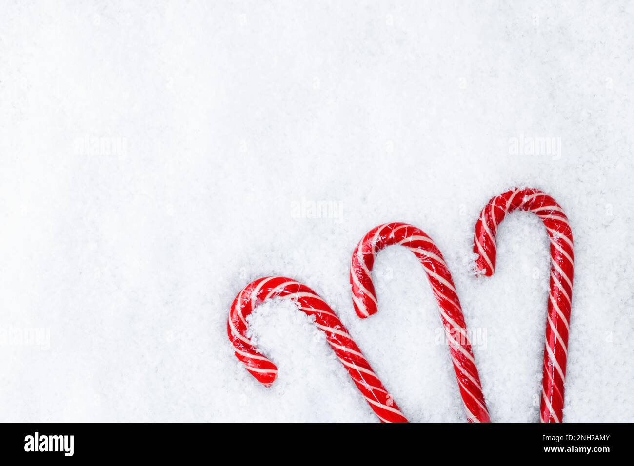 Composition of three Christmas candy canes on a white snowy background ...