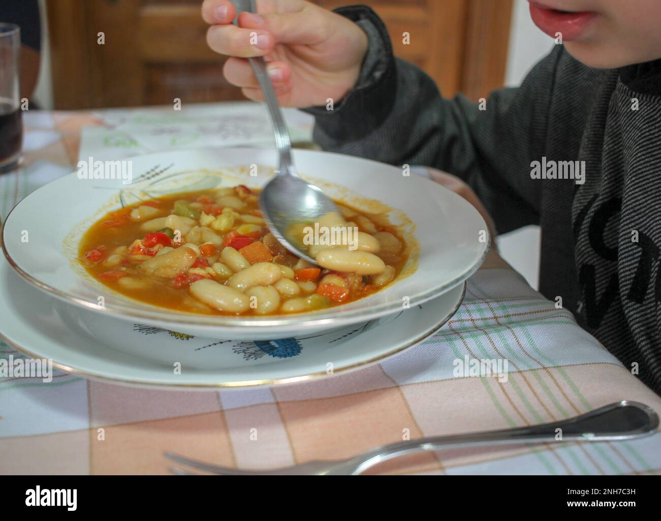 boy eating with a spoon a dish of beans Stock Photo - Alamy