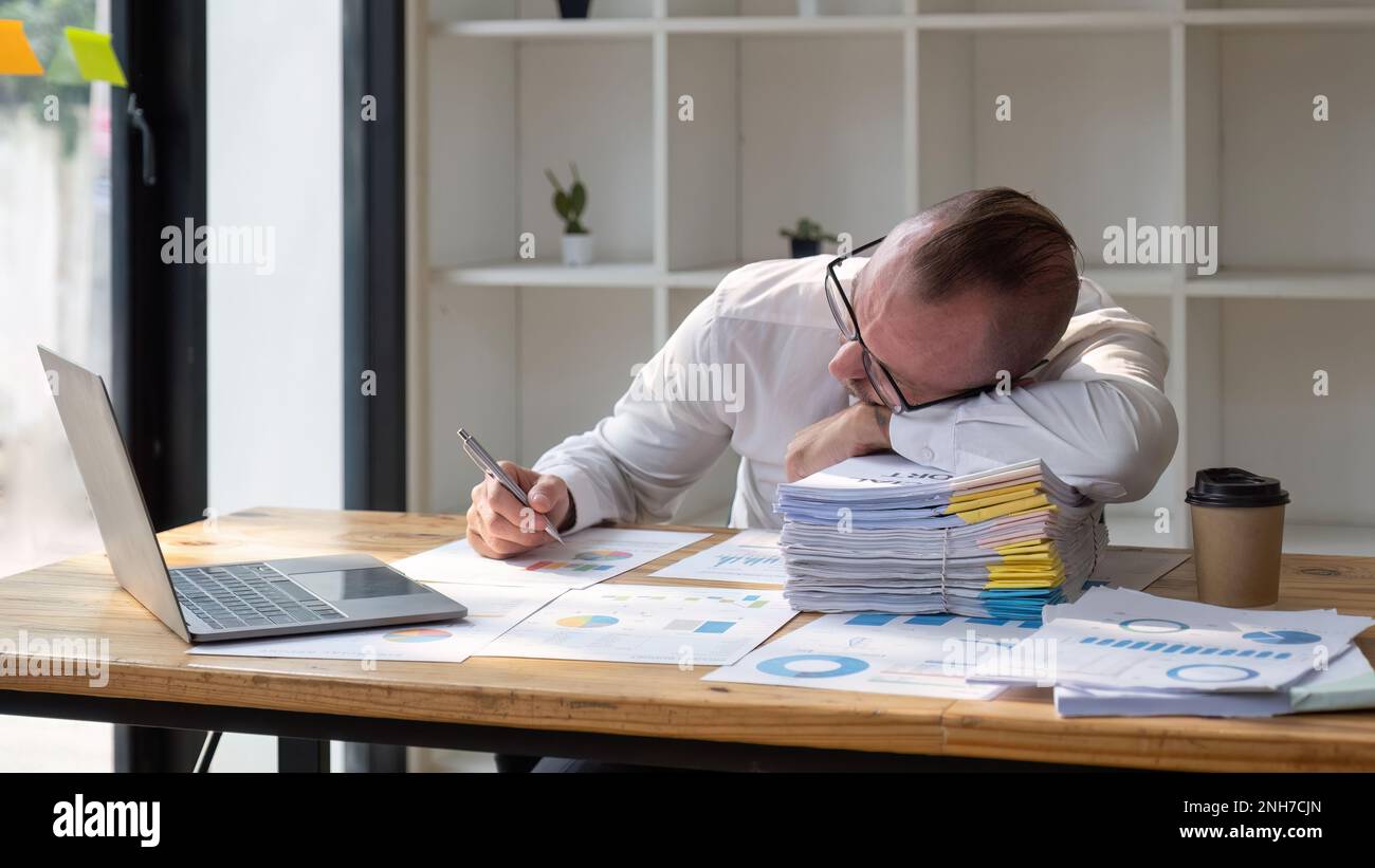 Stressed business man sitting at office workplace. Tired and overworked ...