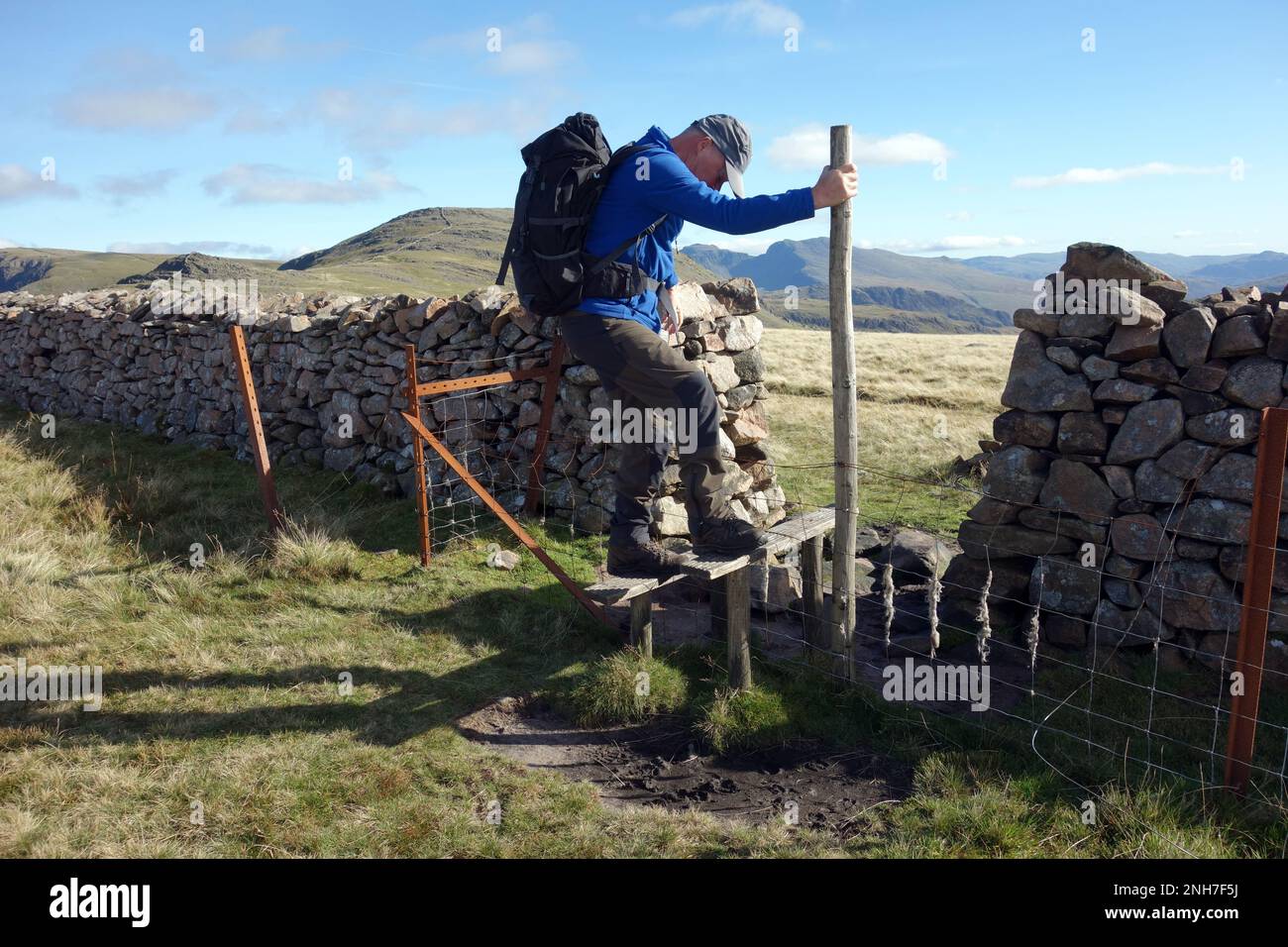 Man Climbing a Wooden Stile in a Stone Wall om the Summit of the ...